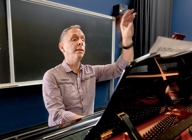 Photo de Robert Filion, au piano, la main gauche levée pour indiquer la ...